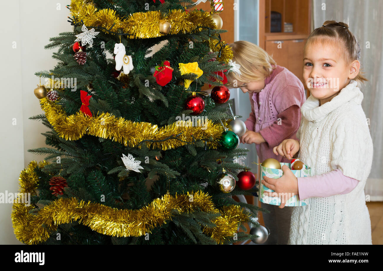 Two smiling little sisters decorating Christmas tree at home Stock ...