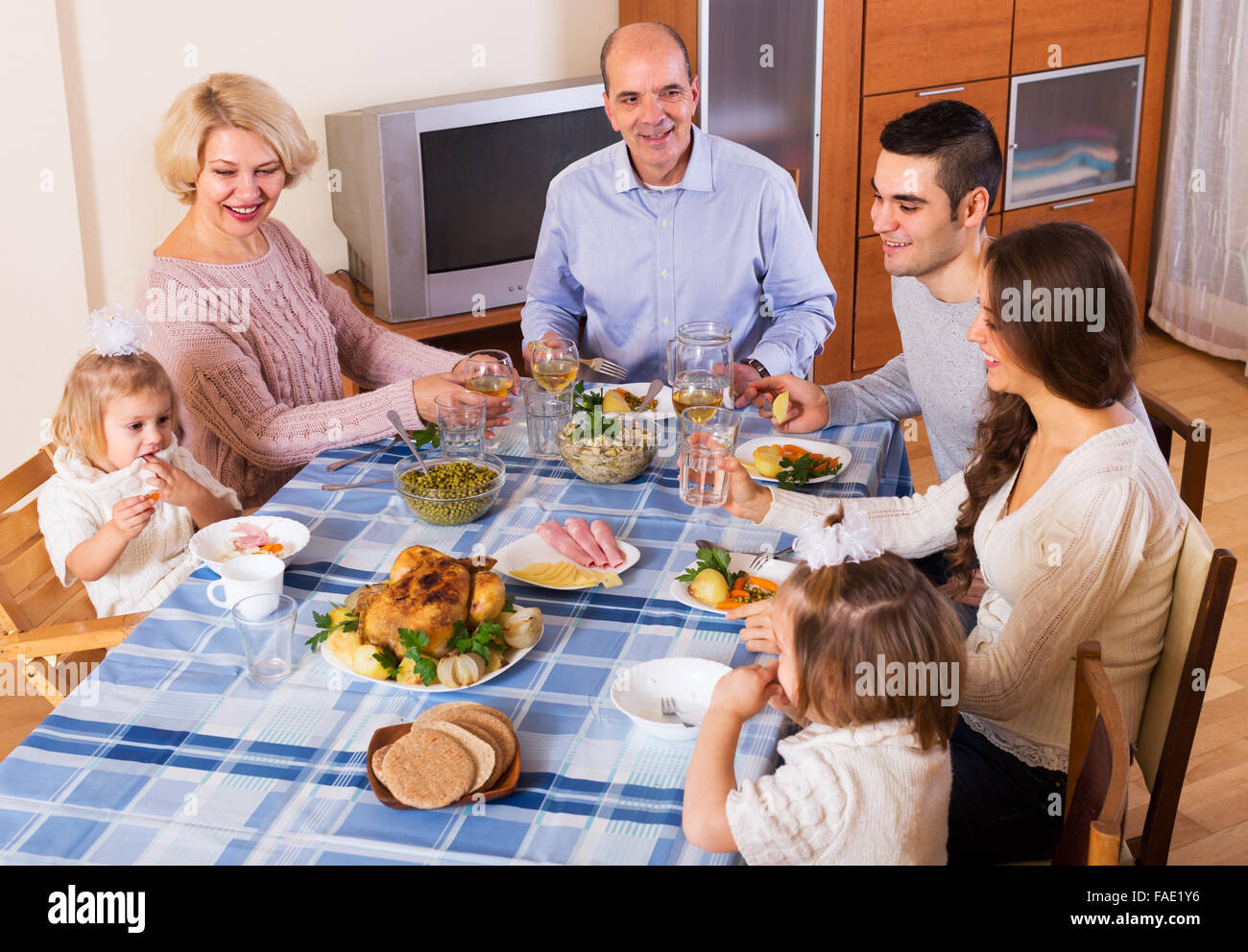 Multigenerational family sitting at the table set for dinner and talks ...