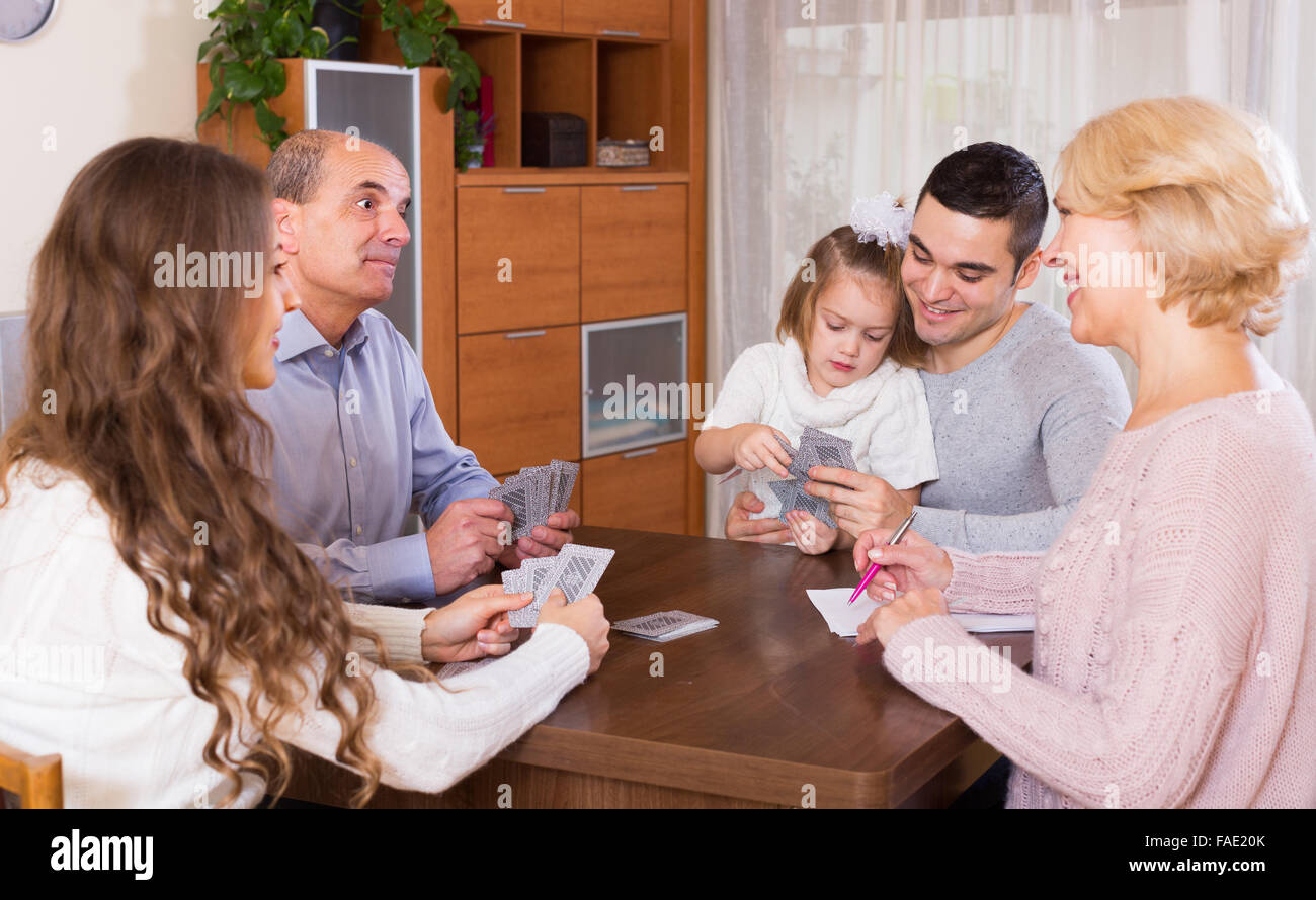 Long family with grand children sitting at table with cards in the room ...