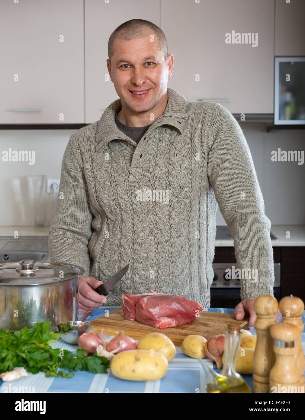 Man with raw meat in his kitchen Stock Photo - Alamy