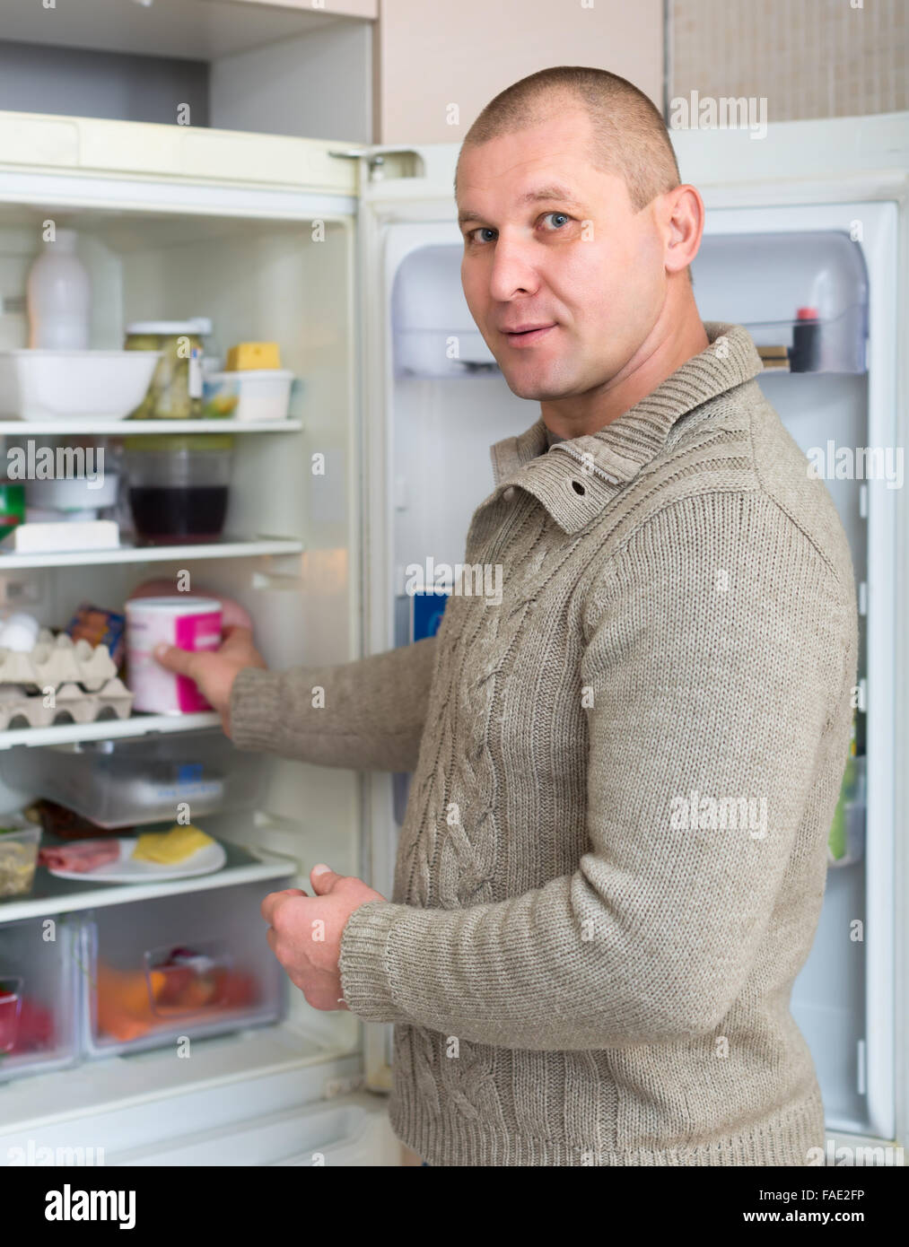 Adult male in the kitchen taking something from fridge to eat Stock ...