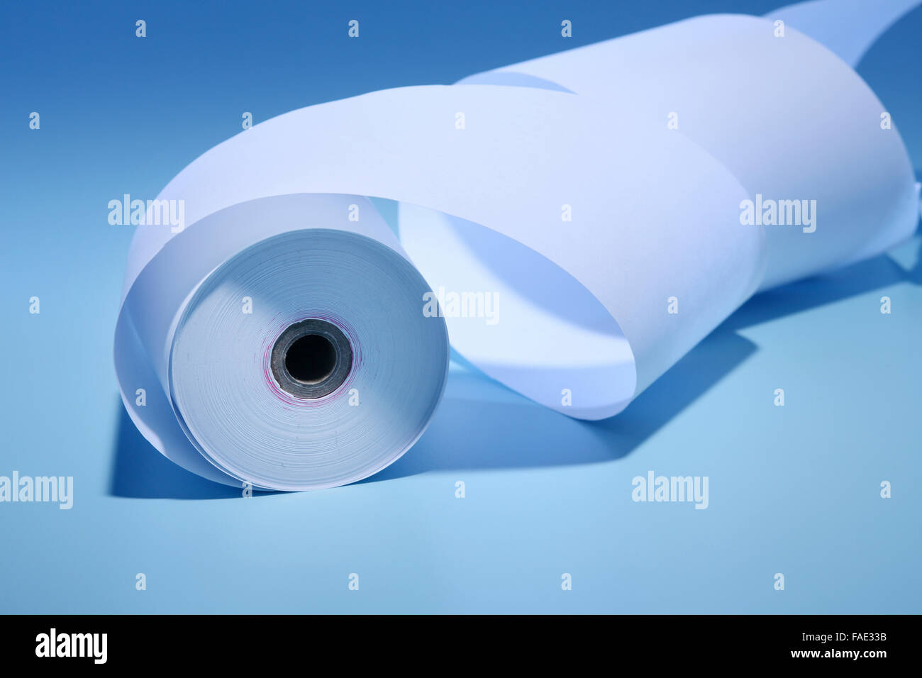 Roll of paper curling on the blue background Stock Photo - Alamy