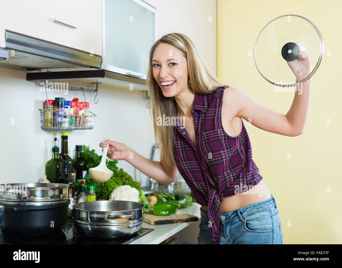 Smiling long-haired beautiful woman cooking soup in the kitchen Stock ...