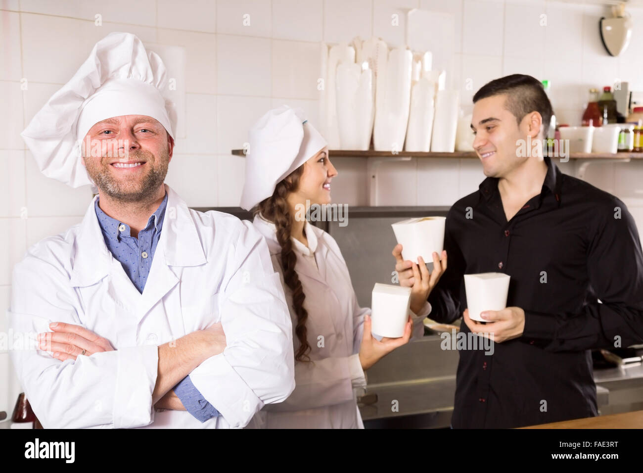 Portrait happy cook and client buying take-away food at eating house ...