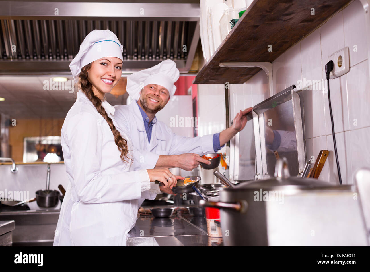 Couple of happy smiling cooks working together at kitchen in take-away ...