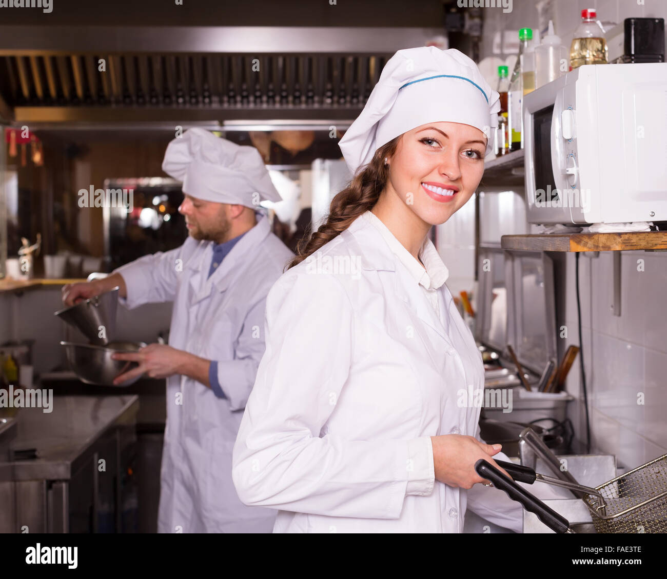 Happy smiling cooks working together at kitchen in take-away restaurant ...