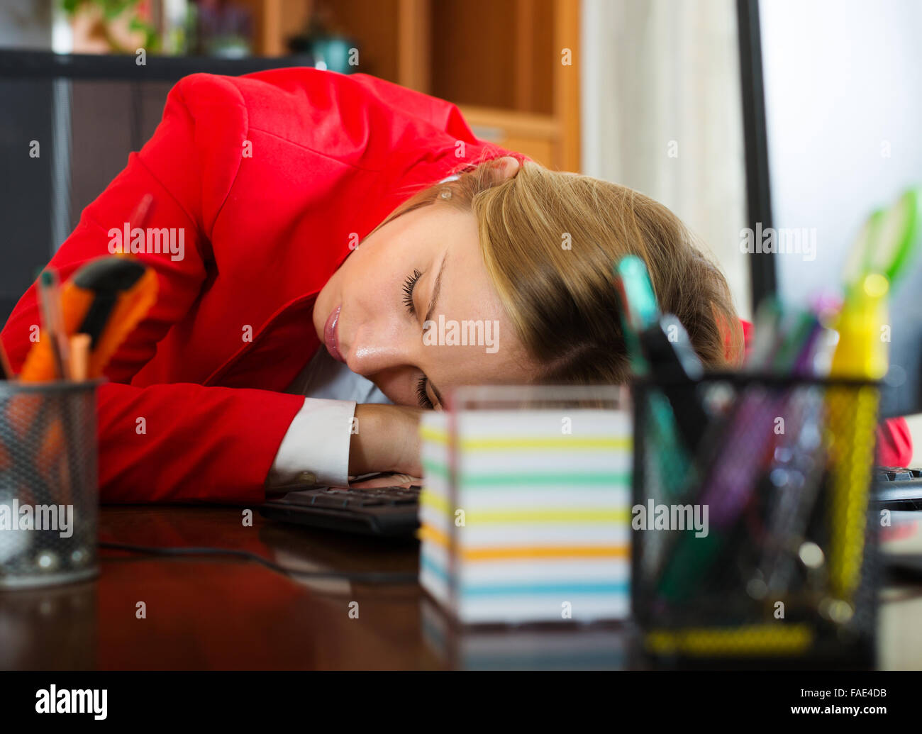 tired businesswoman in red sleeping at office desk Stock Photo - Alamy