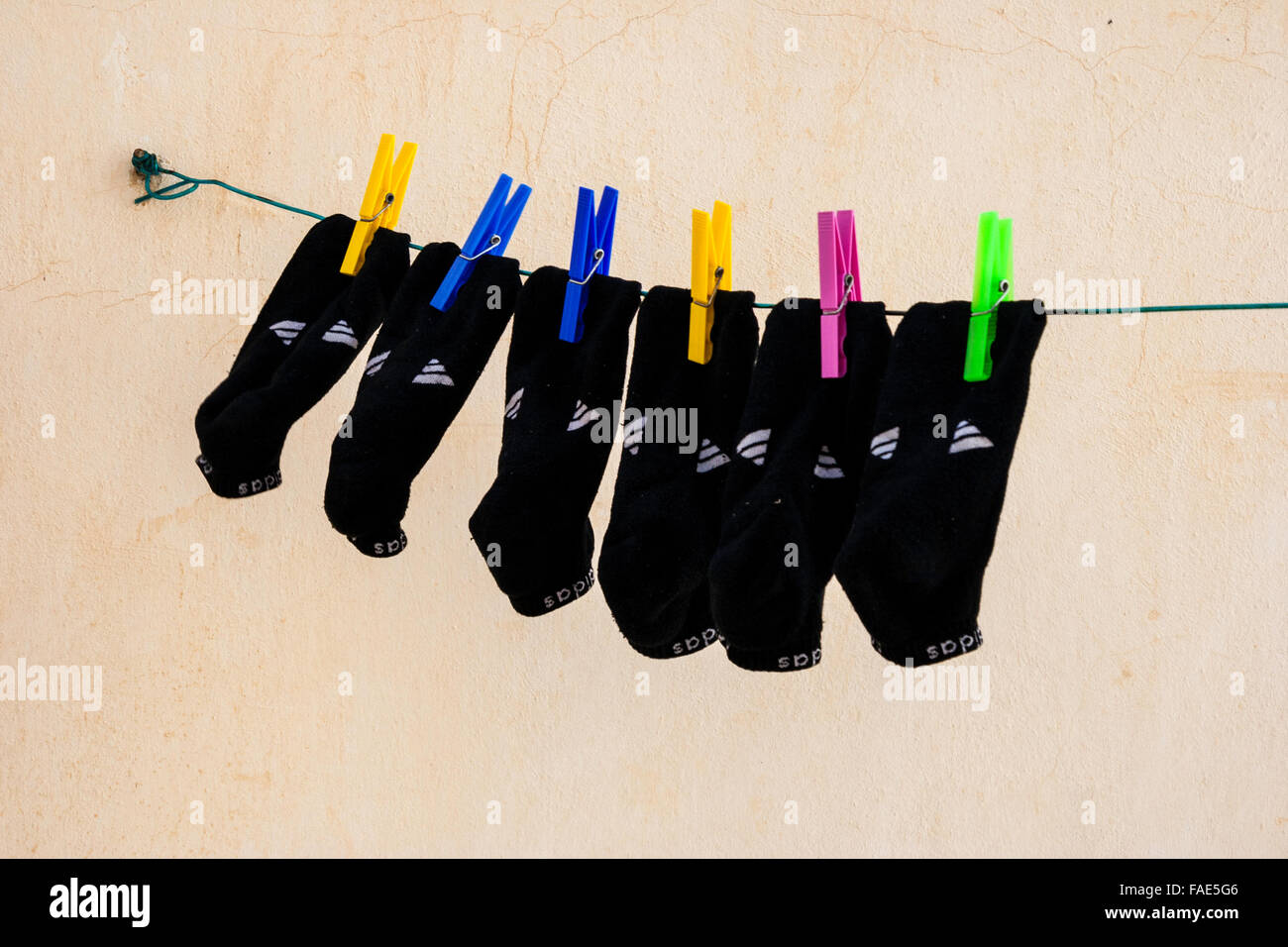 Green washing line with three pairs of Adidas black socks with logos ...