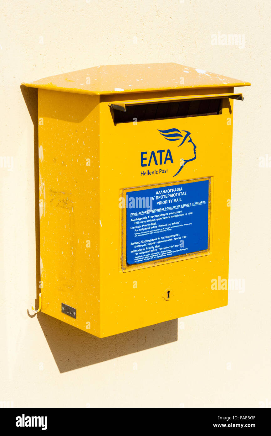 Greek post box. Yellow box with blue lettering attached to whitewashed ...