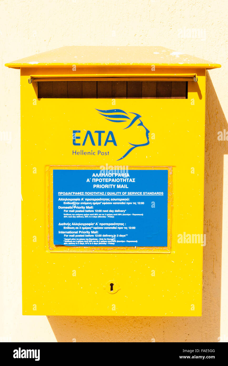 Greek post box. Yellow box with blue lettering attached to whitewashed ...