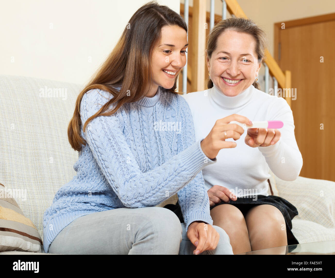 happy daughter showing pregnancy test to her mother at sofa Stock Photo ...