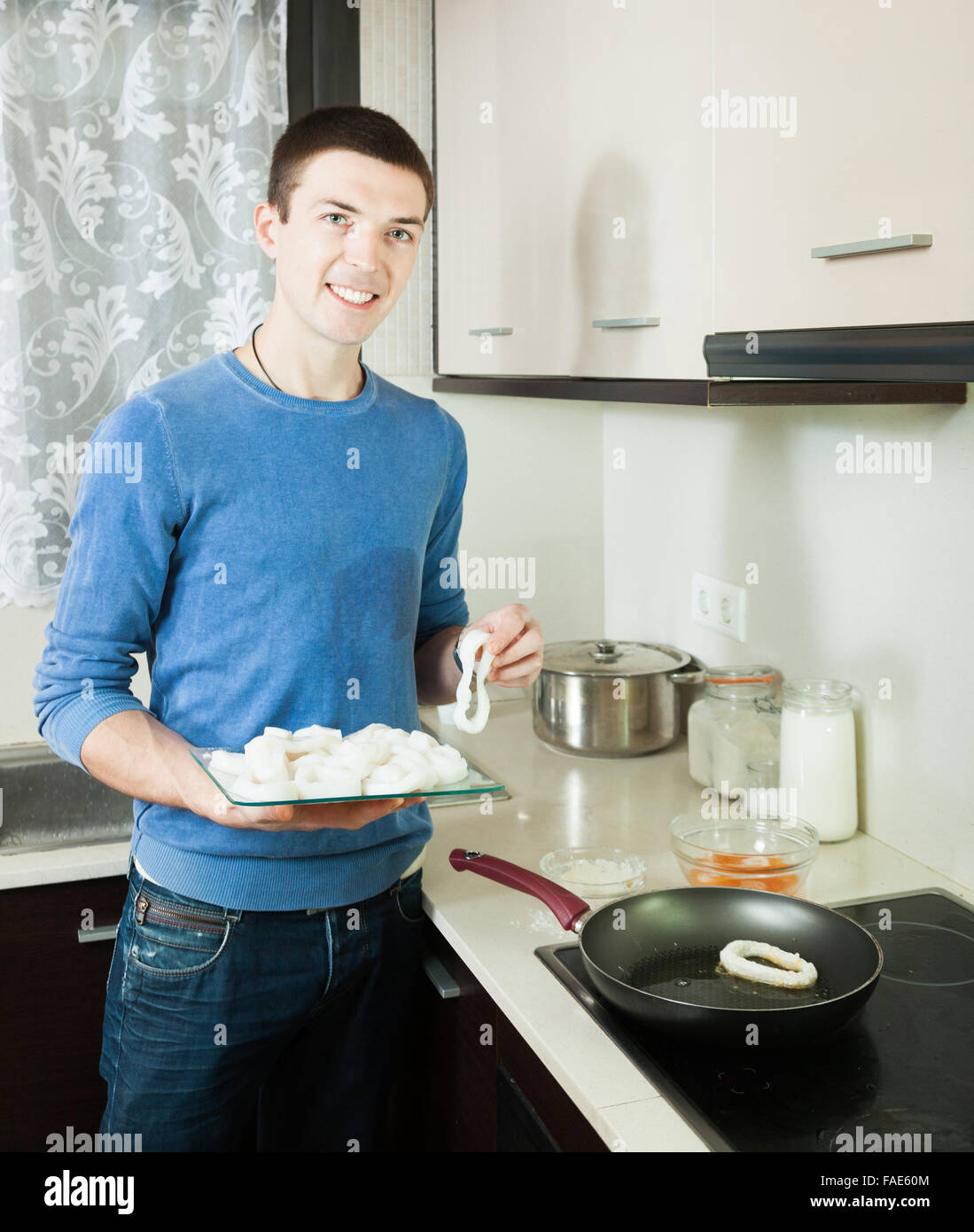 Happy guy cooking squid rings in batter Stock Photo - Alamy