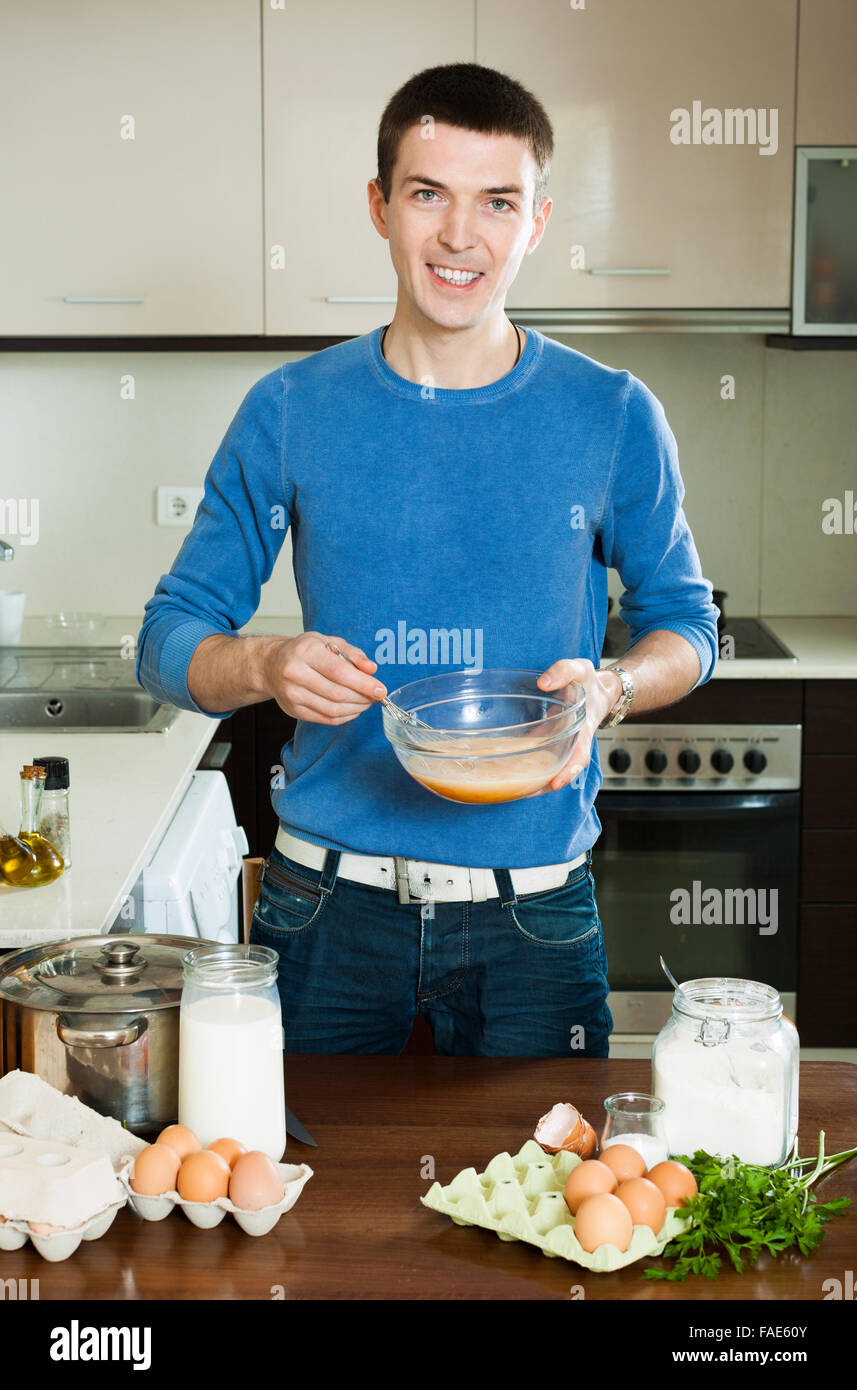 Happy european man cooking scrambled eggs in home kitchen Stock Photo ...