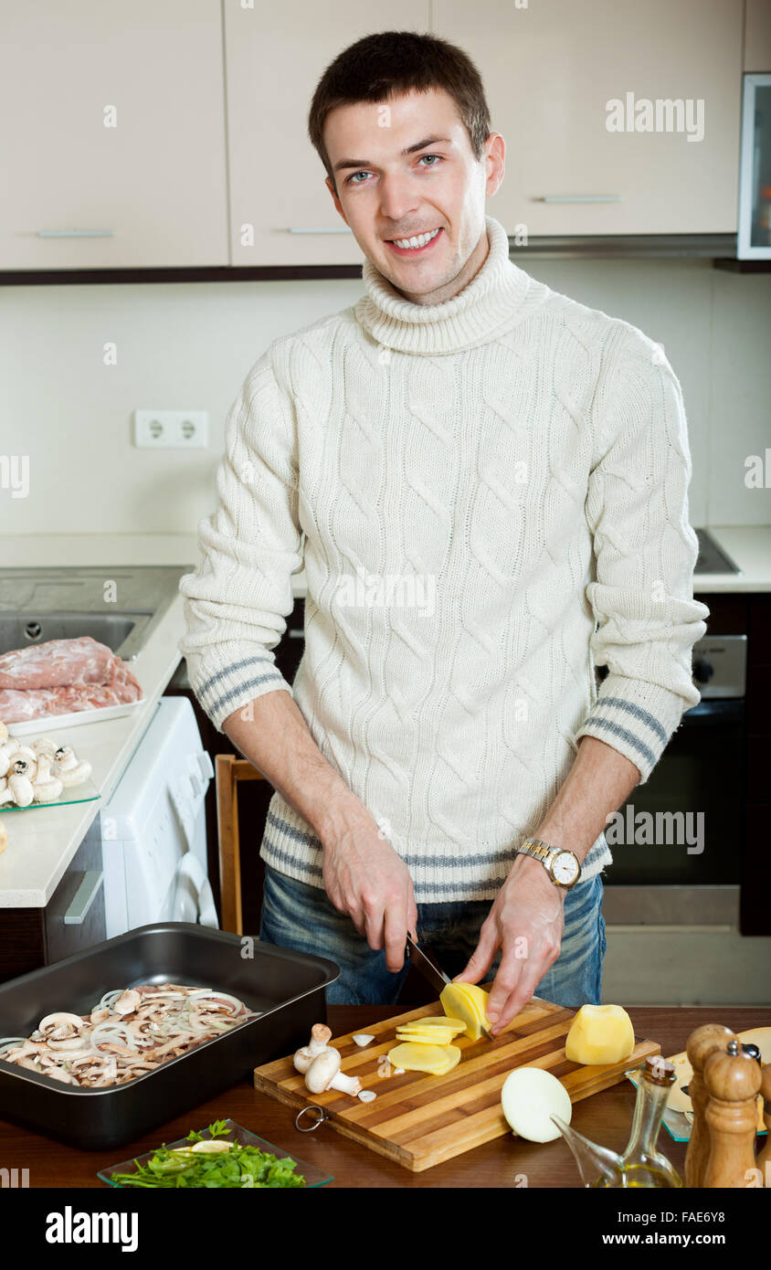 Ordinary guy cooking french-style veal. Cutting potatoes Stock Photo ...