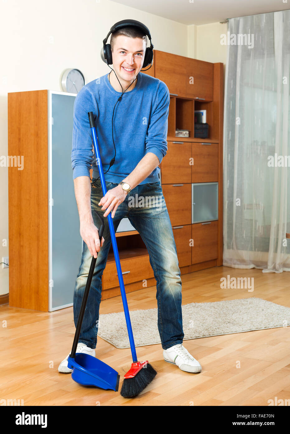 Happy guy sweeping the floor in home Stock Photo - Alamy