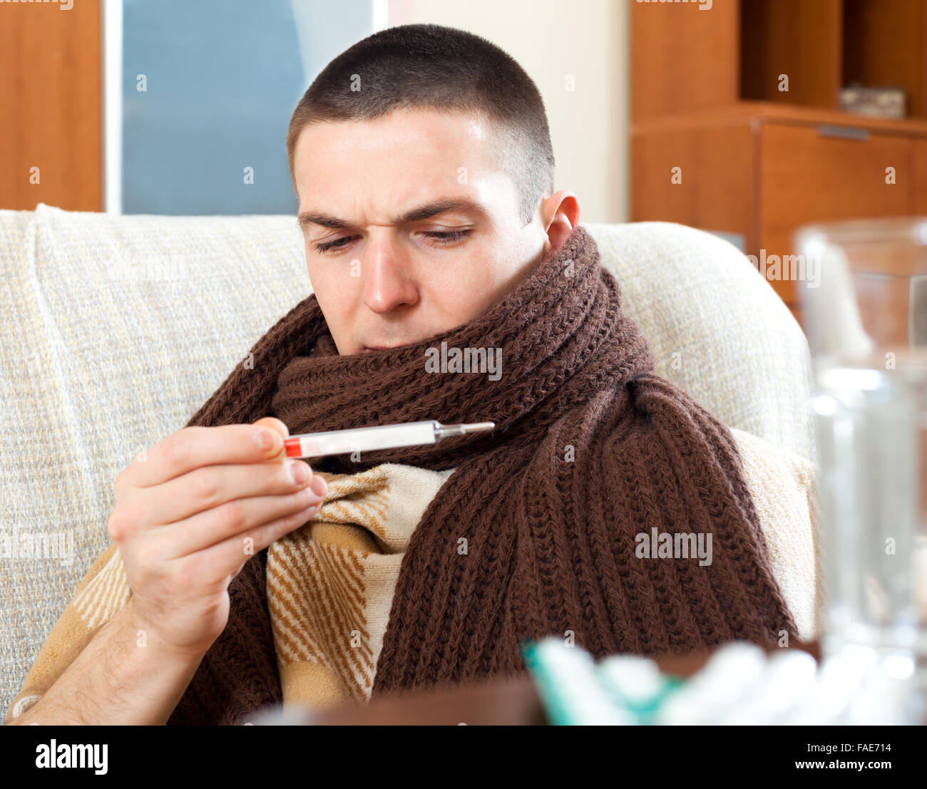 Sick ordinary man looking by thermometer at home Stock Photo - Alamy