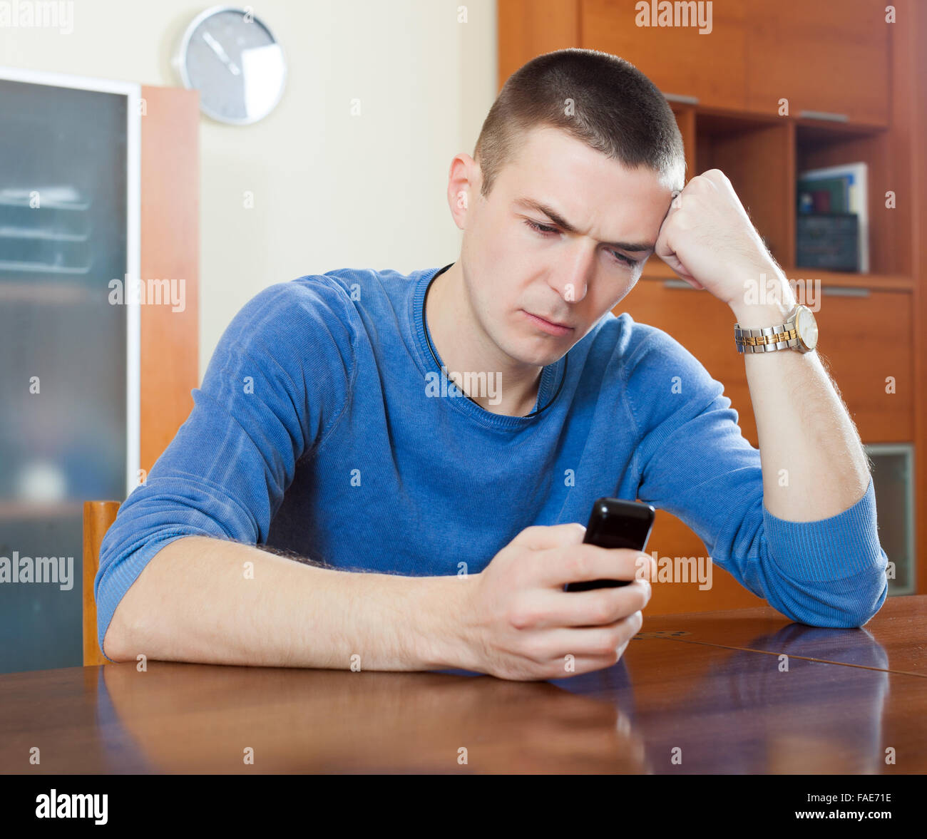 Sad guy crying after phone call in his living room Stock Photo - Alamy