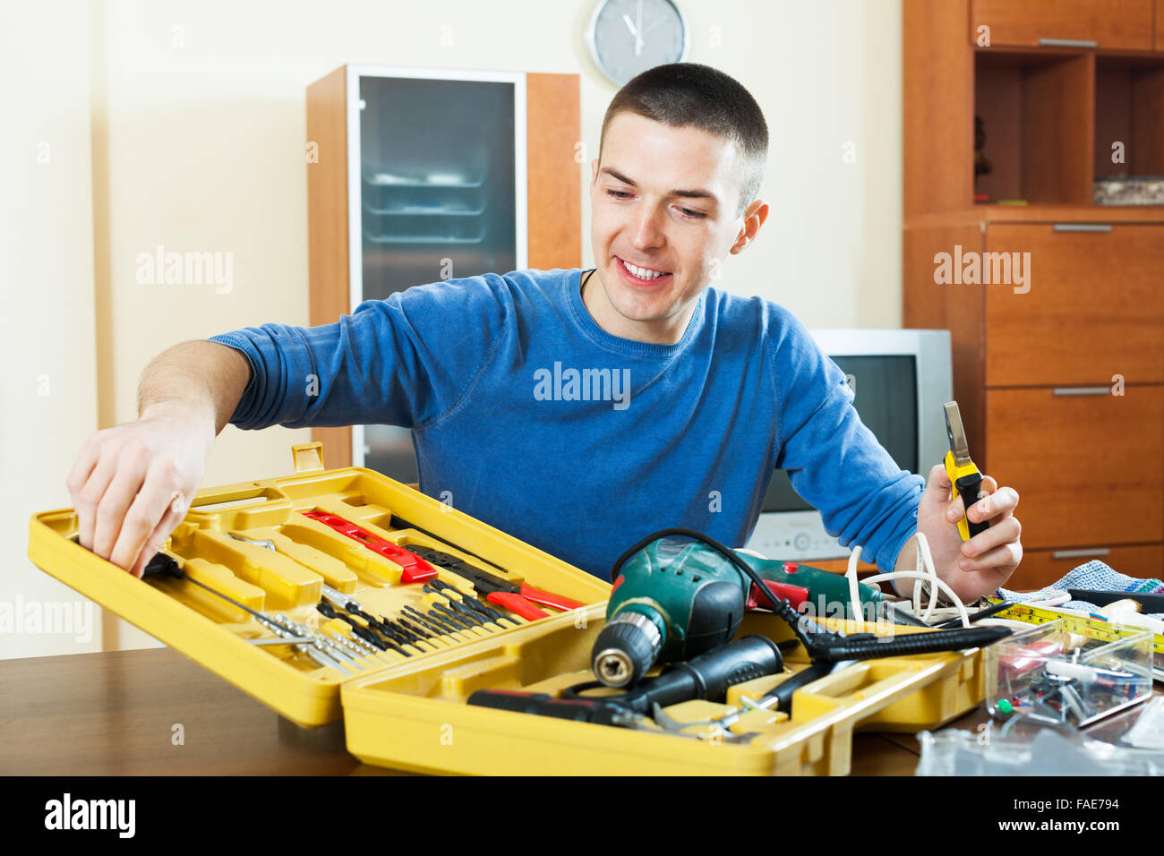 Young happy smiling man organizing tools in toolbox in home interior ...