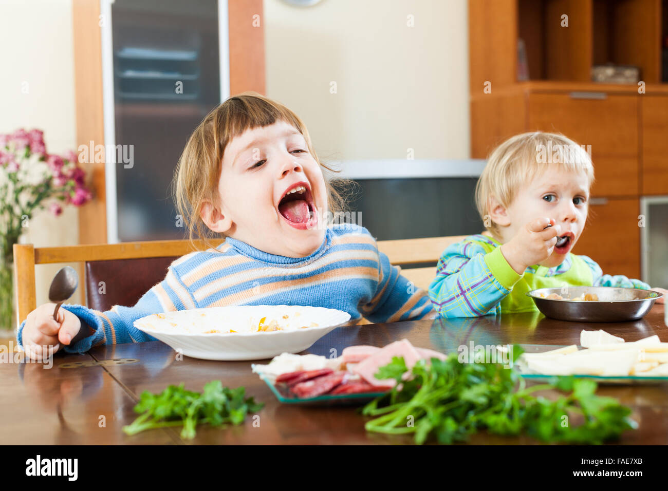 happy emotional girls eating food from plates at table Stock Photo - Alamy