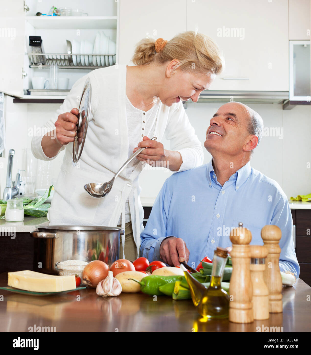 smiling elderly couple and cooking together in domestic kitchen Stock ...
