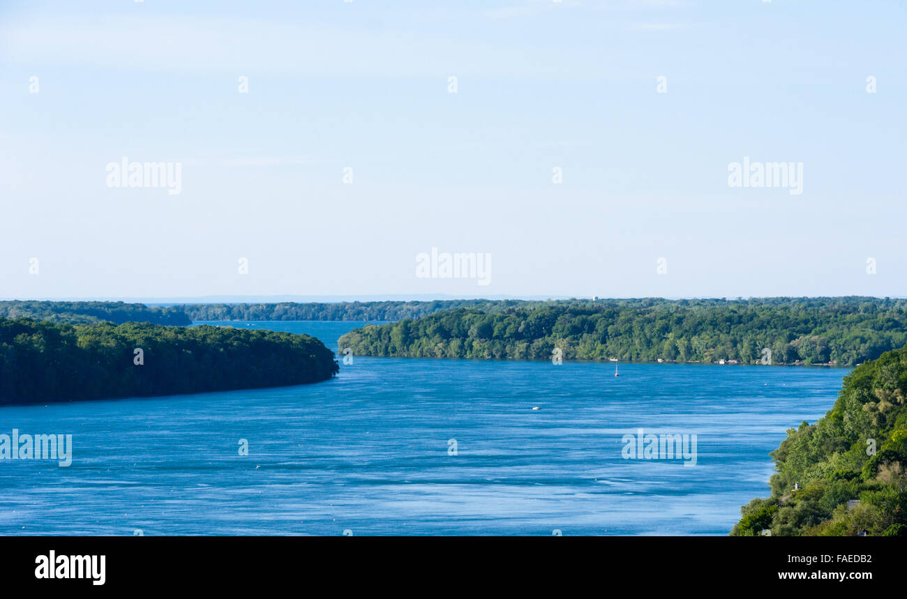 Large wide river winding through forested area under white empty sky ...