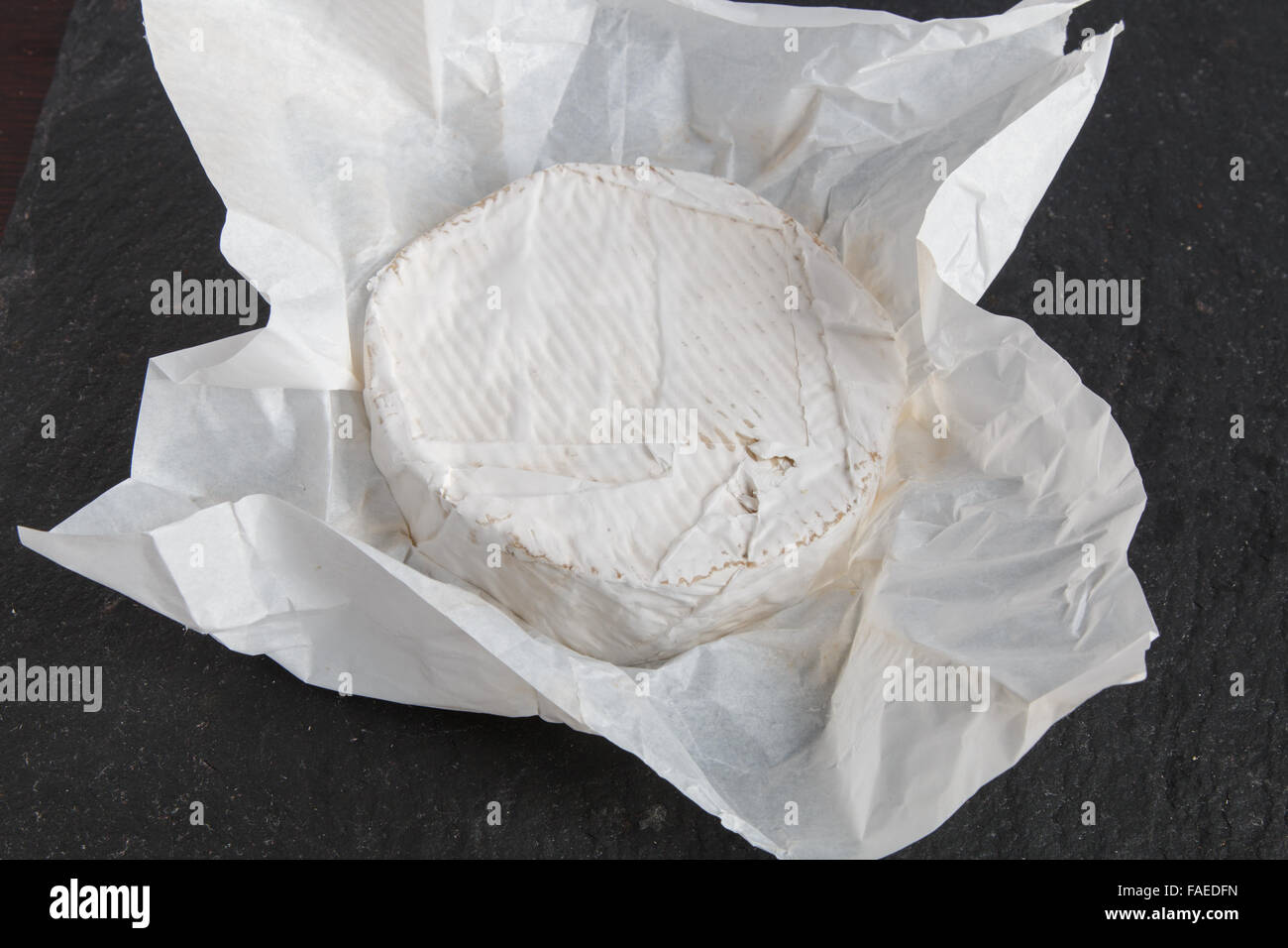 Wrapped English Brie soft cheese on a grey slate background Stock Photo ...