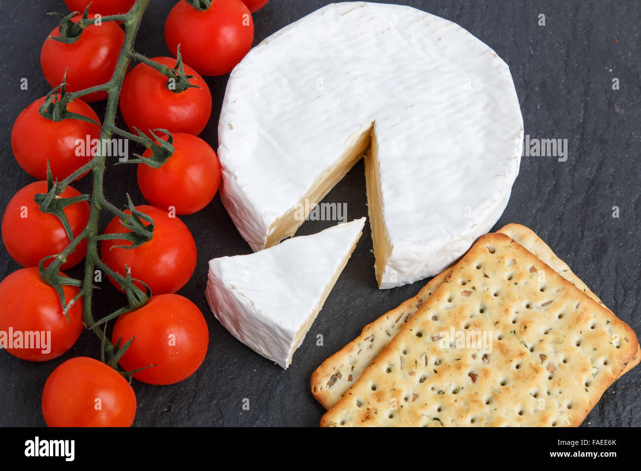 Brie soft cheese with crackers and tomato on a grey slate board Stock ...