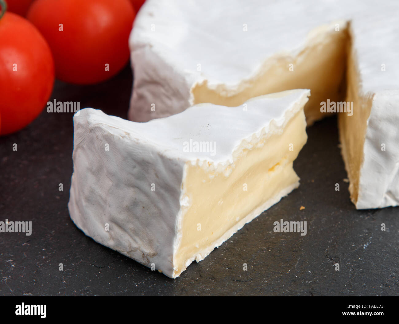 Brie soft cheese with tomato on a grey slate board. Selective Focus ...
