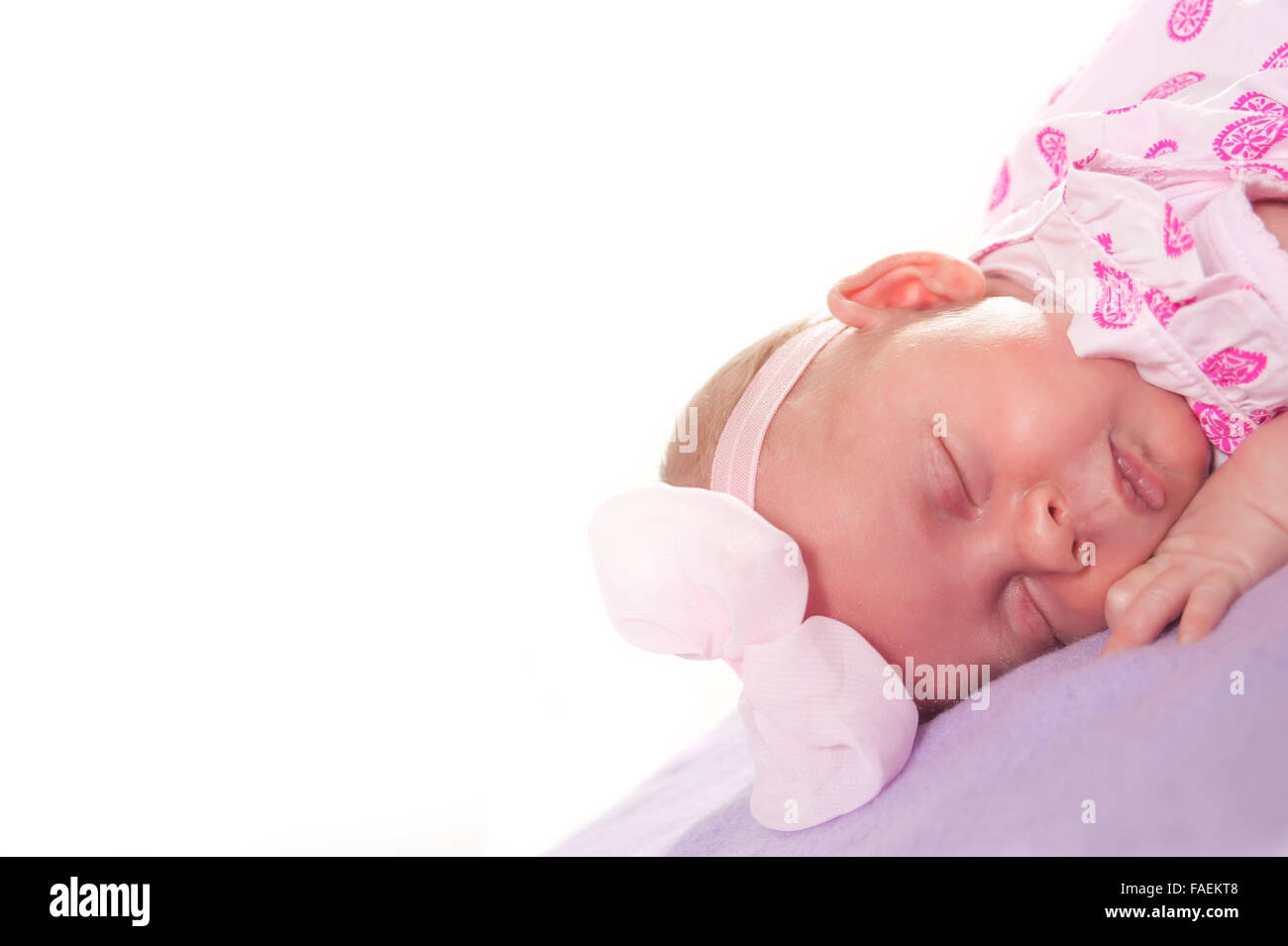 Newborn baby girl slipping on her tummy close up on a white background ...