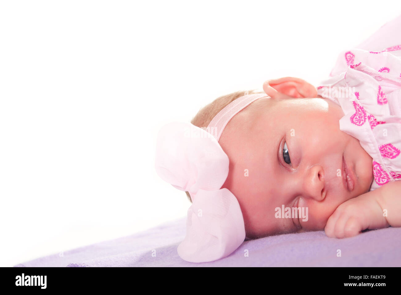 Newborn baby girl slipping on her tummy close up on a white background ...