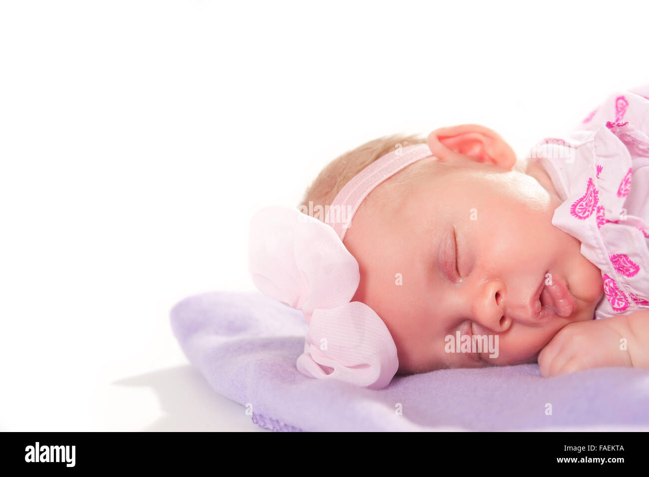 Newborn baby girl slipping on her tummy close up on a white background ...