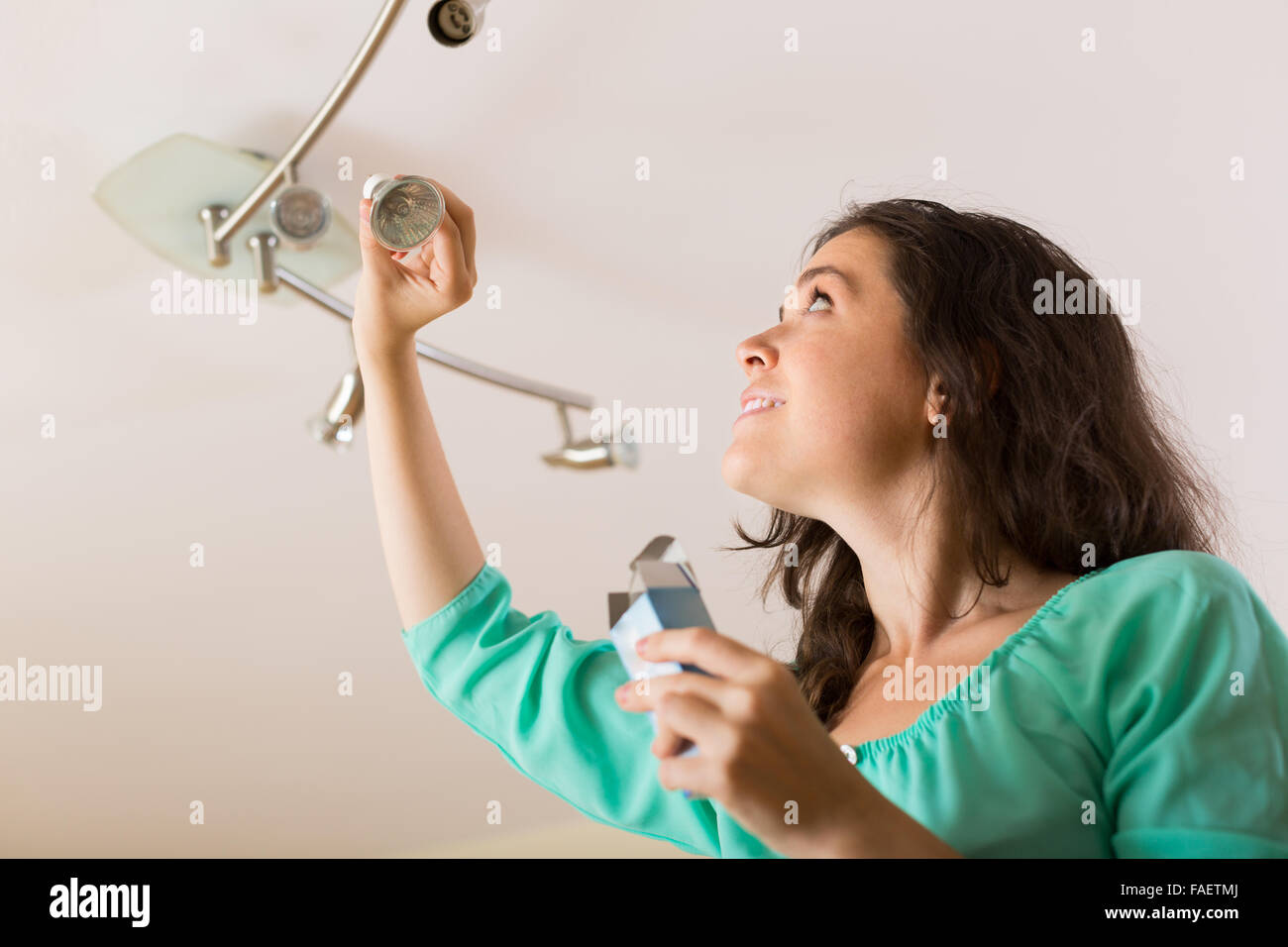 Young smiling woman changing light bulb at her home Stock Photo - Alamy