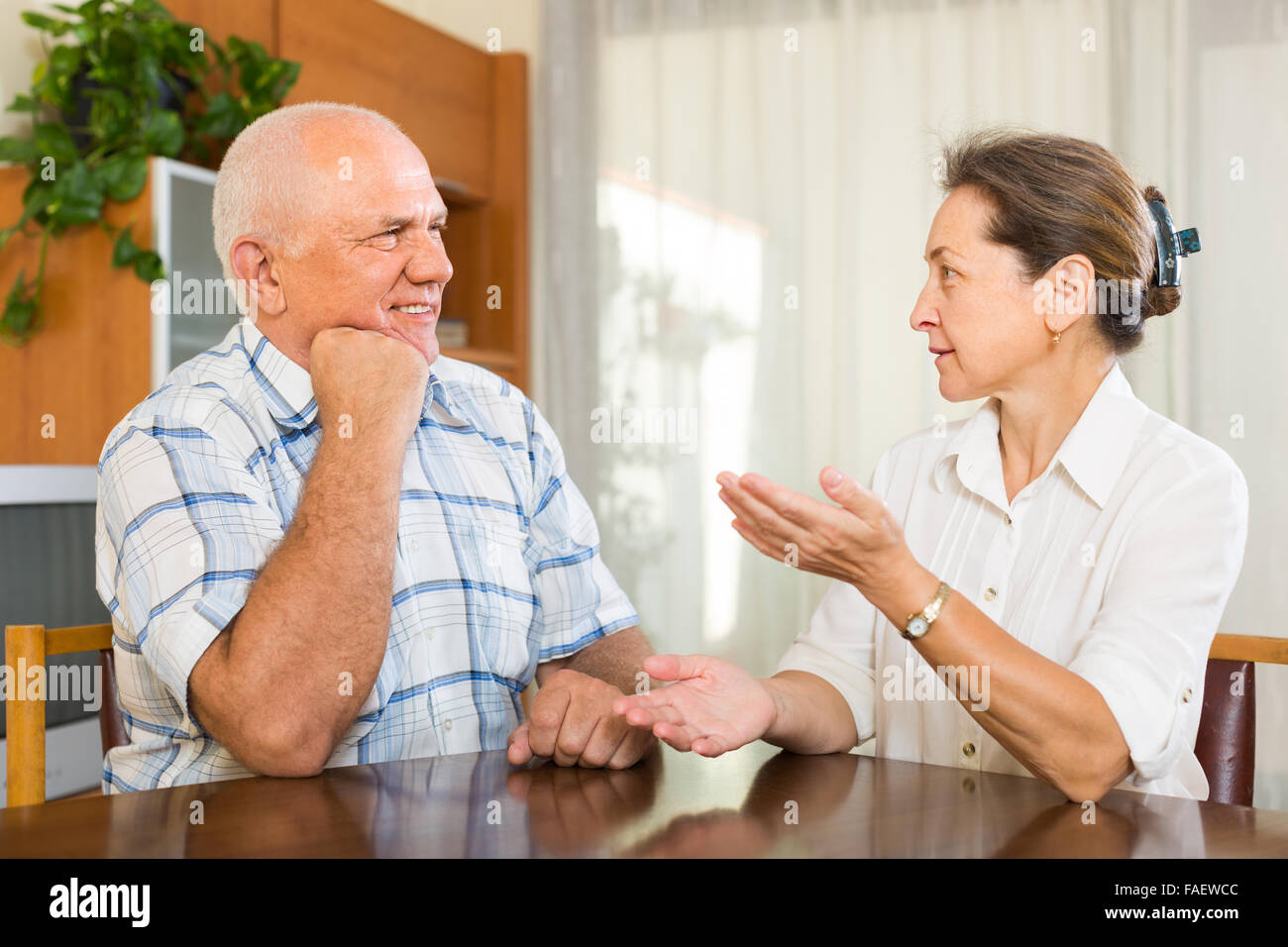Indoor portrait of elderly couple talking together in home interior ...