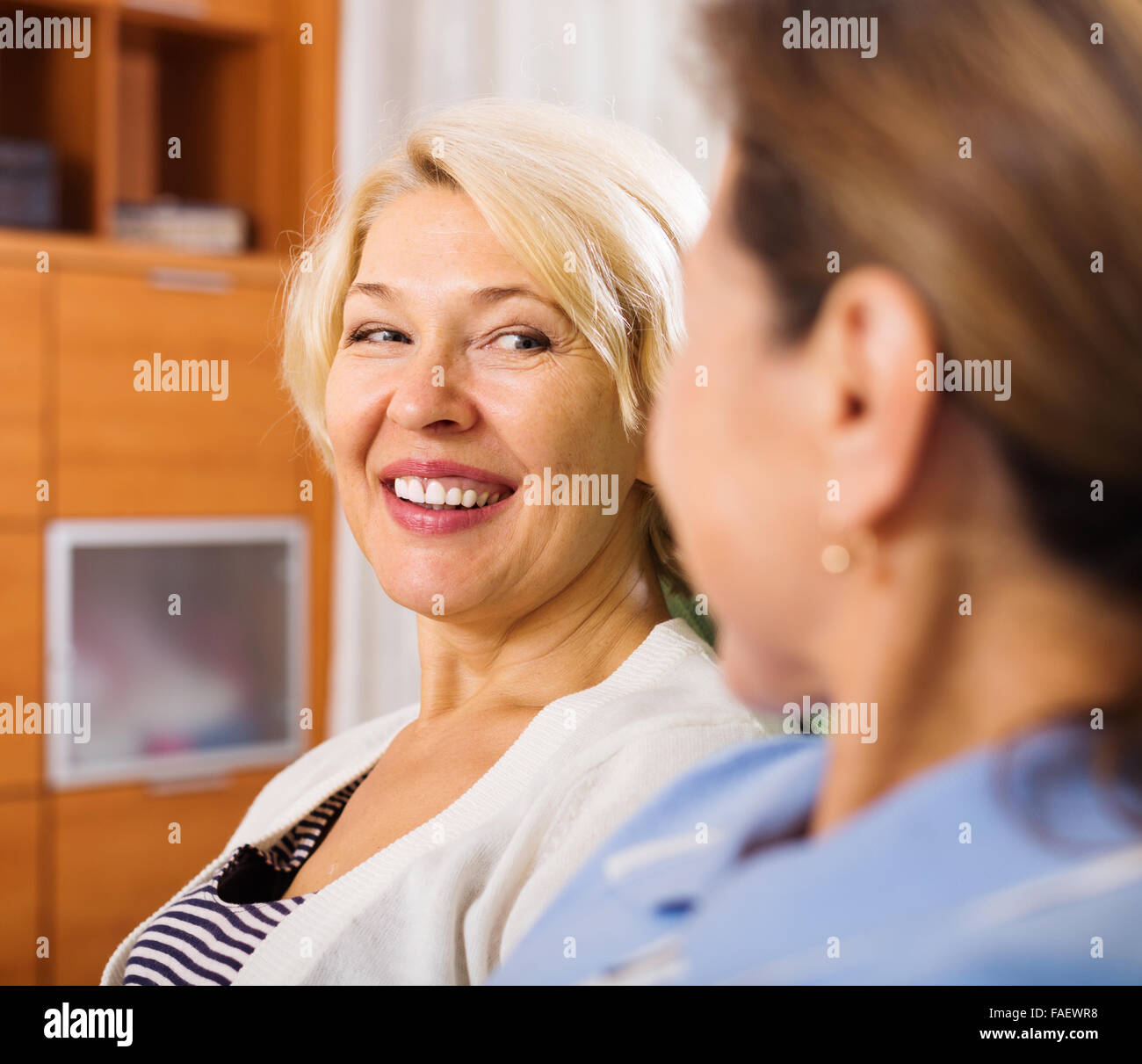 two happy mature women talking at home interior Stock Photo - Alamy