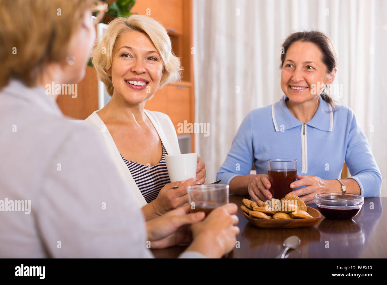 Happy female friends talking during tea drinking at home. Focus on ...