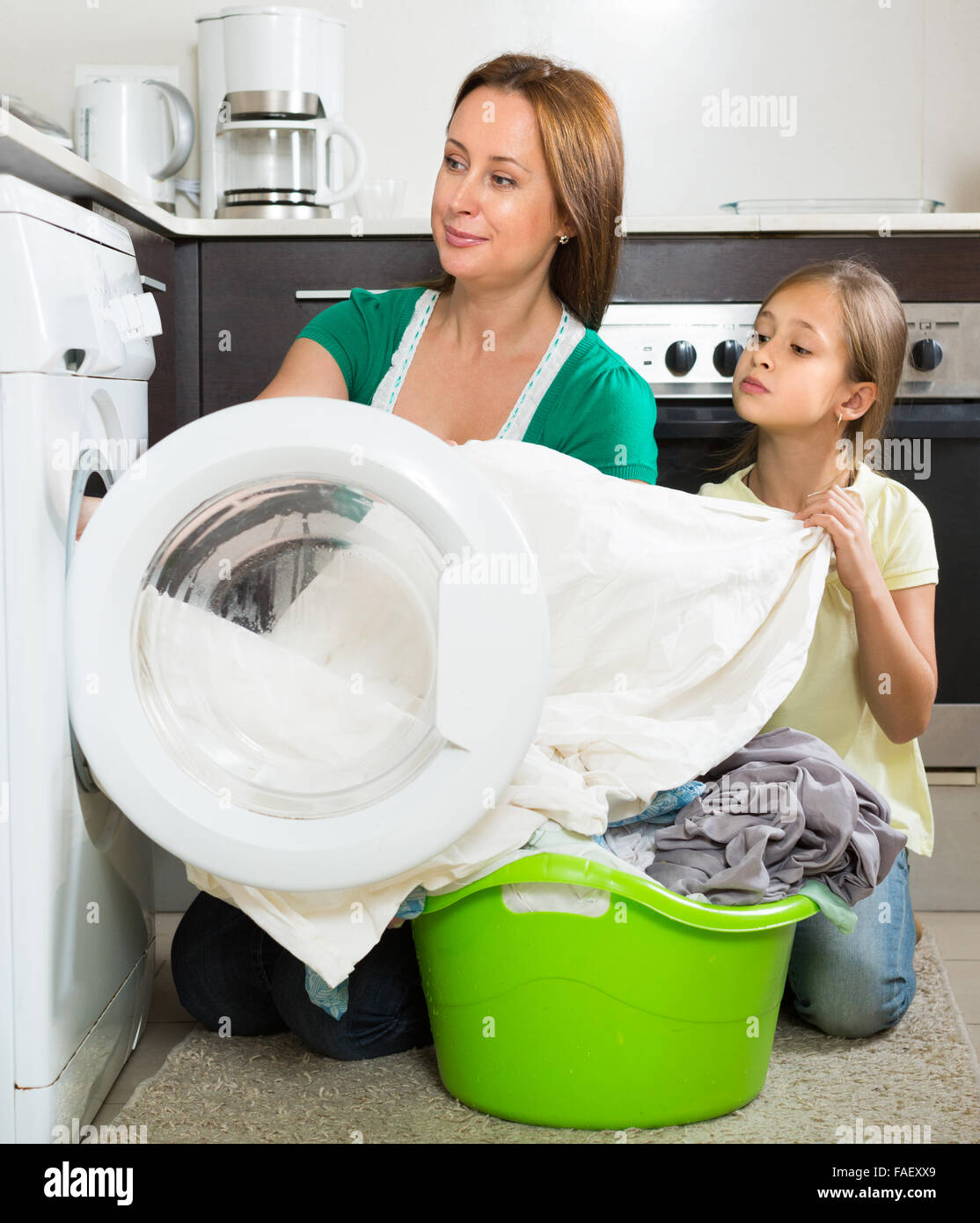 Home laundry. Happy woman with little daughter using washing machine at ...