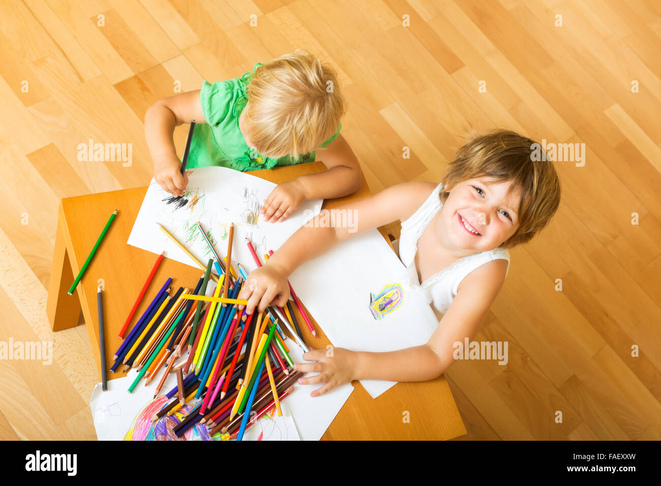 Two little children sketching with paper and pencils at home Stock ...
