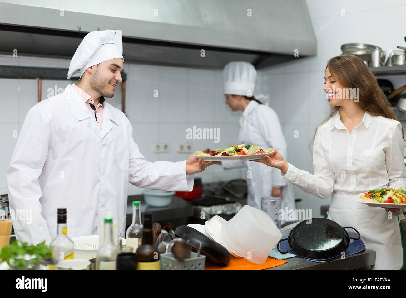 Cook gives to positive waitress plates with prepared food Stock Photo ...