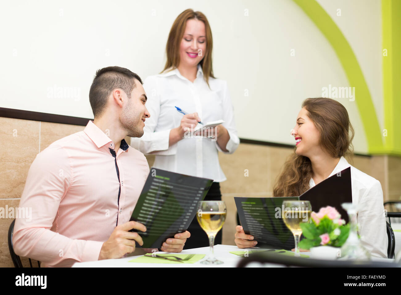 Handsome man with beautiful smiling girlfriend making order in cafe ...
