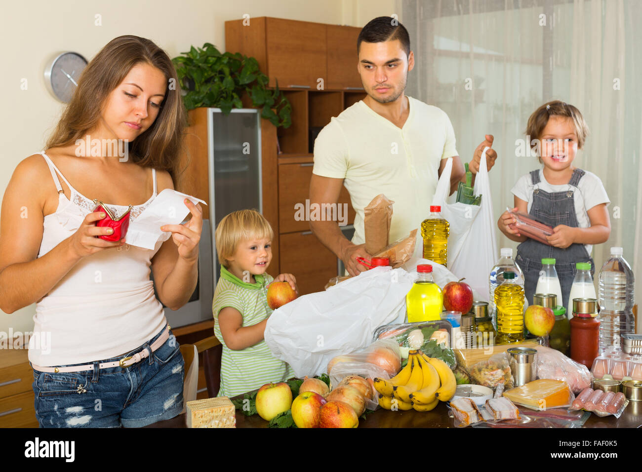 Poor family of four with bags of food at home. Focus on woman Stock ...