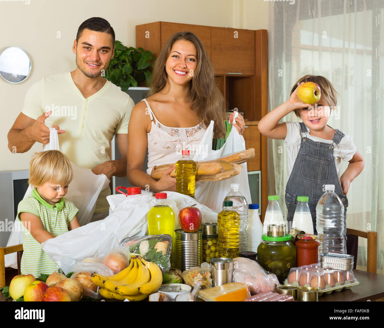 Happy family with little children sorting purchased food out indoor ...