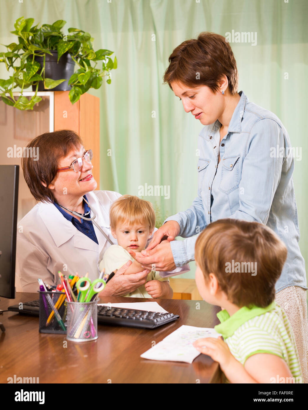friendly pediatrician doctor examining children with mother at clinic ...
