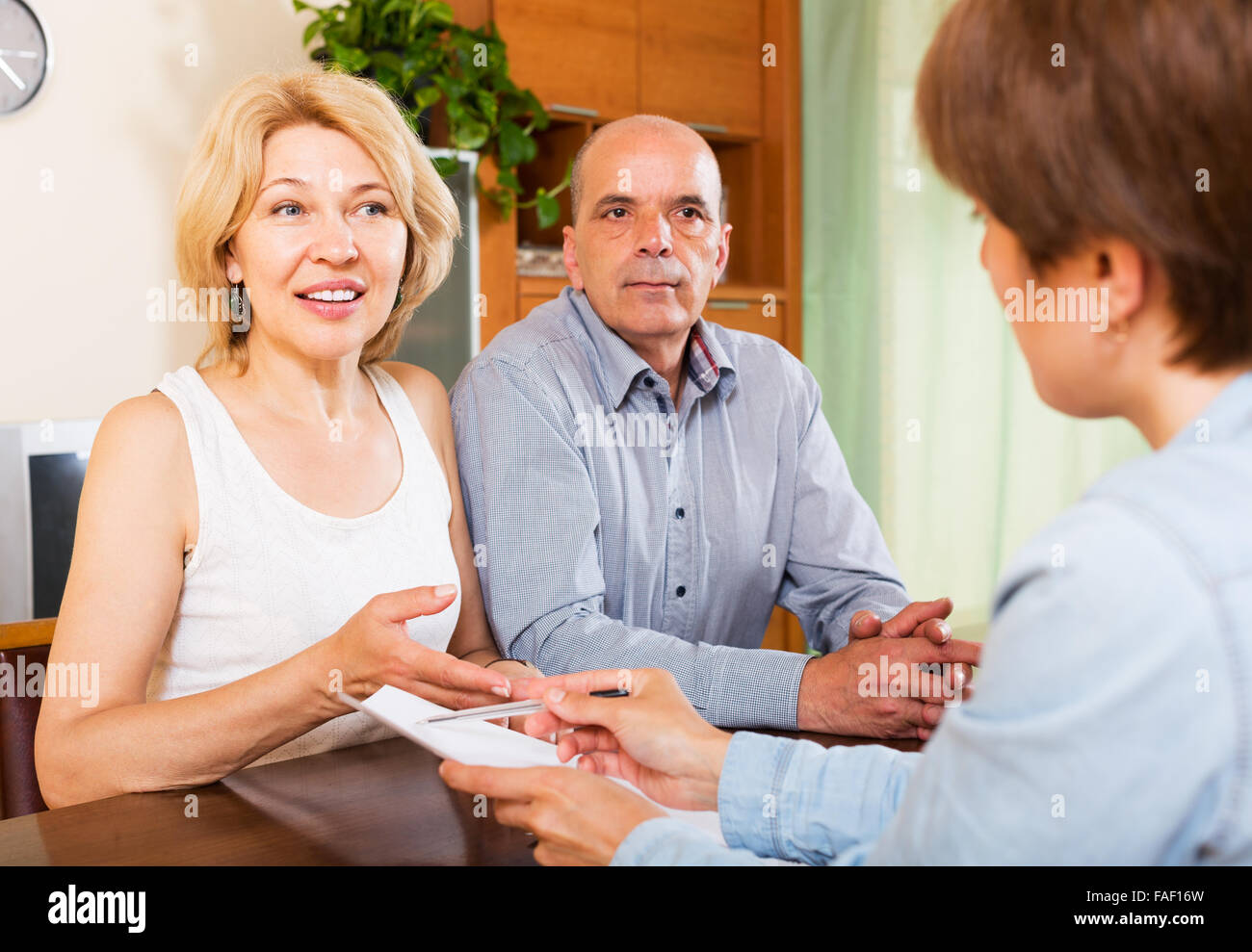 Couple of pensioners talking with manager at home or office Stock Photo ...