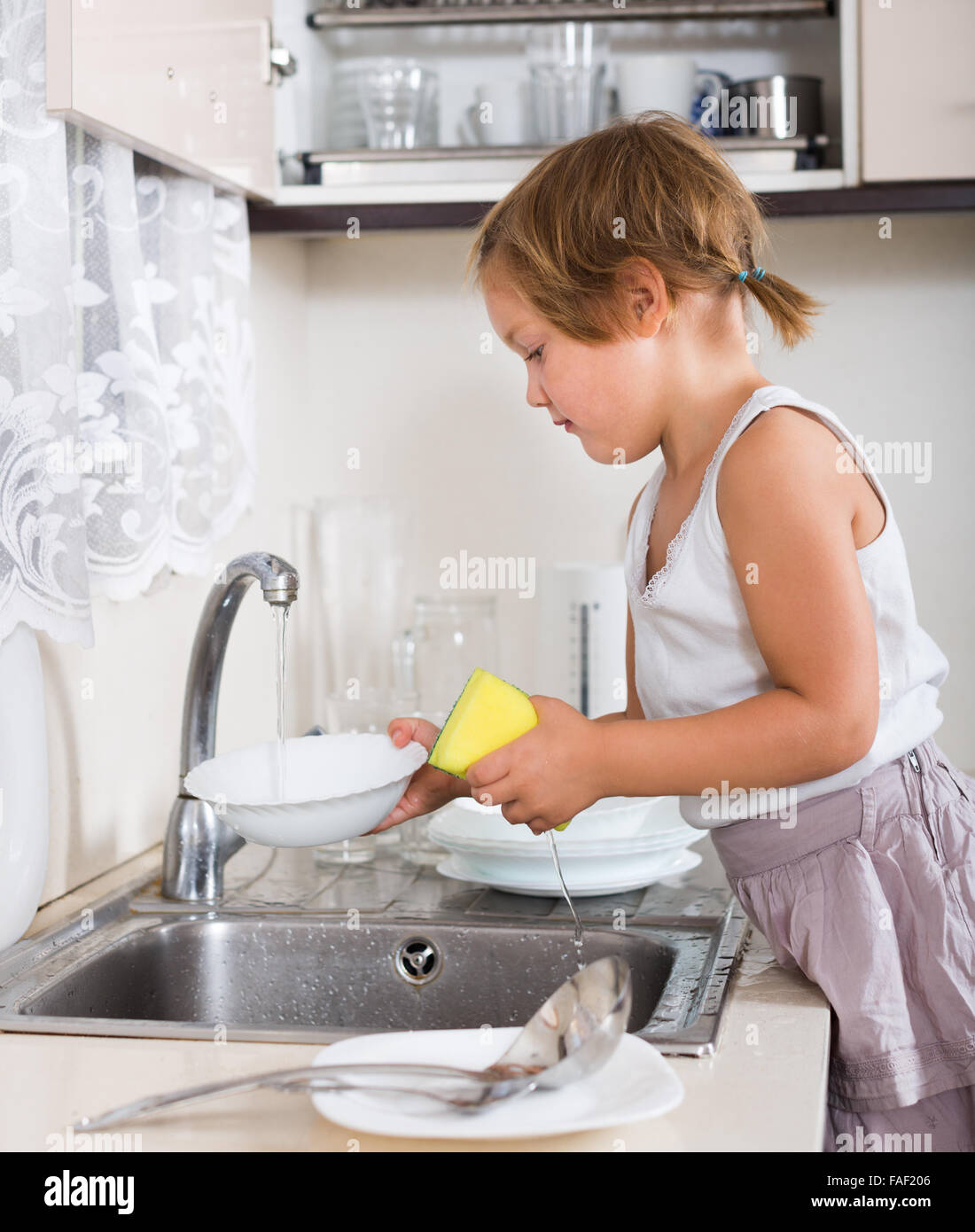 Cute little girl washing dishes in the kitchen Stock Photo - Alamy