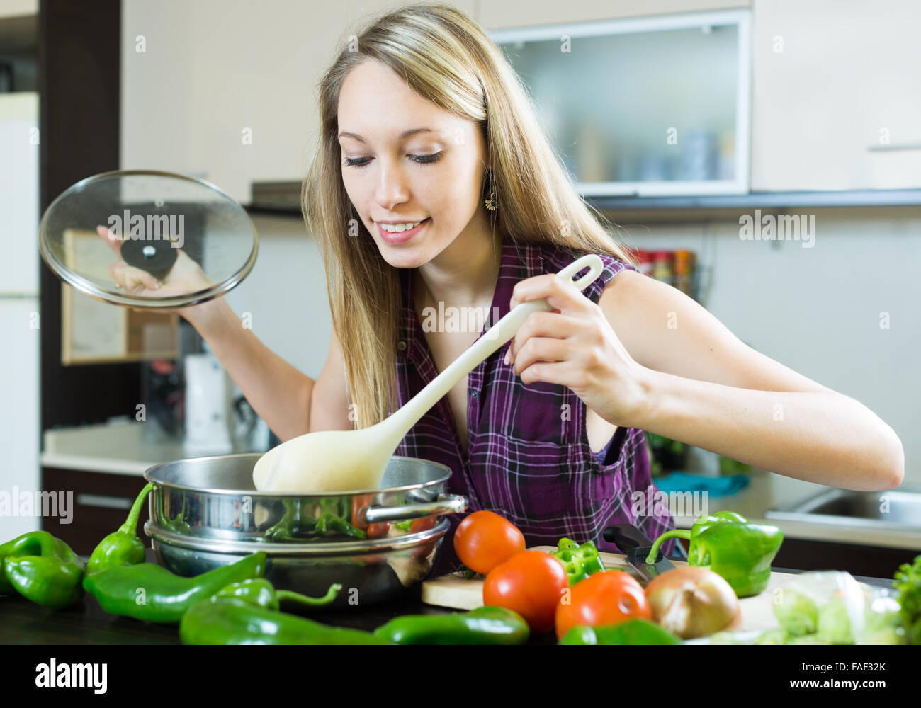 Smiling woman with long-hair cooking soup in the kitchen Stock Photo ...