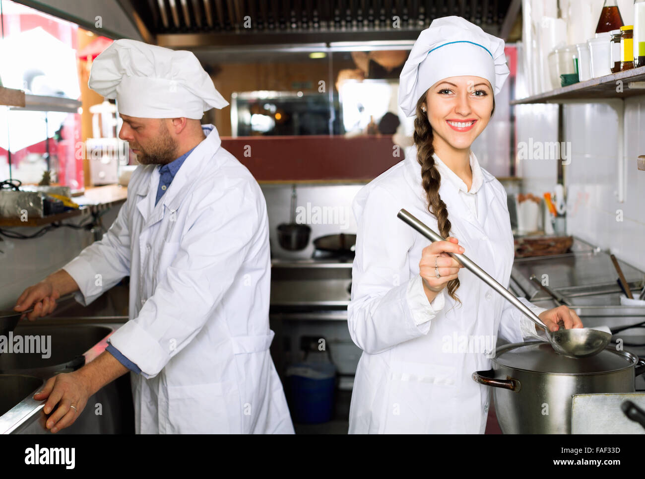 Smiling professional chefs working at take-away restaurant kitchen ...