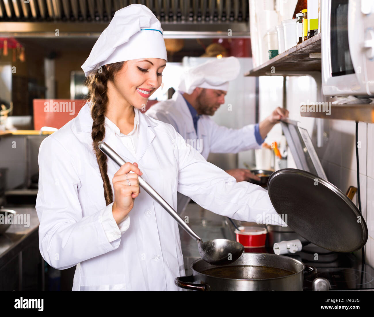 Cheerful chef and cook working at take-away restaurant kitchen Stock ...