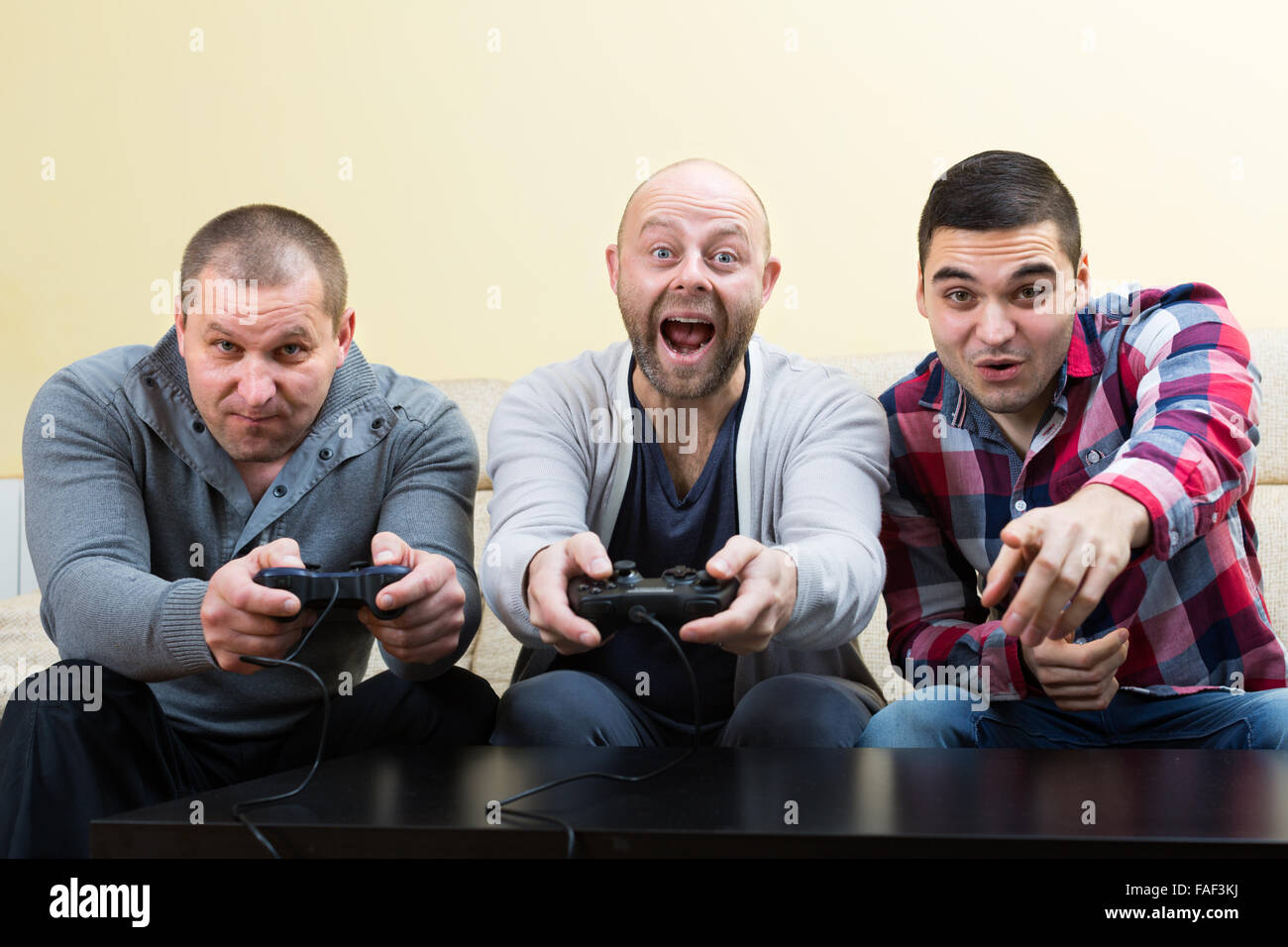Three shouting males playing video games at house party Stock Photo - Alamy