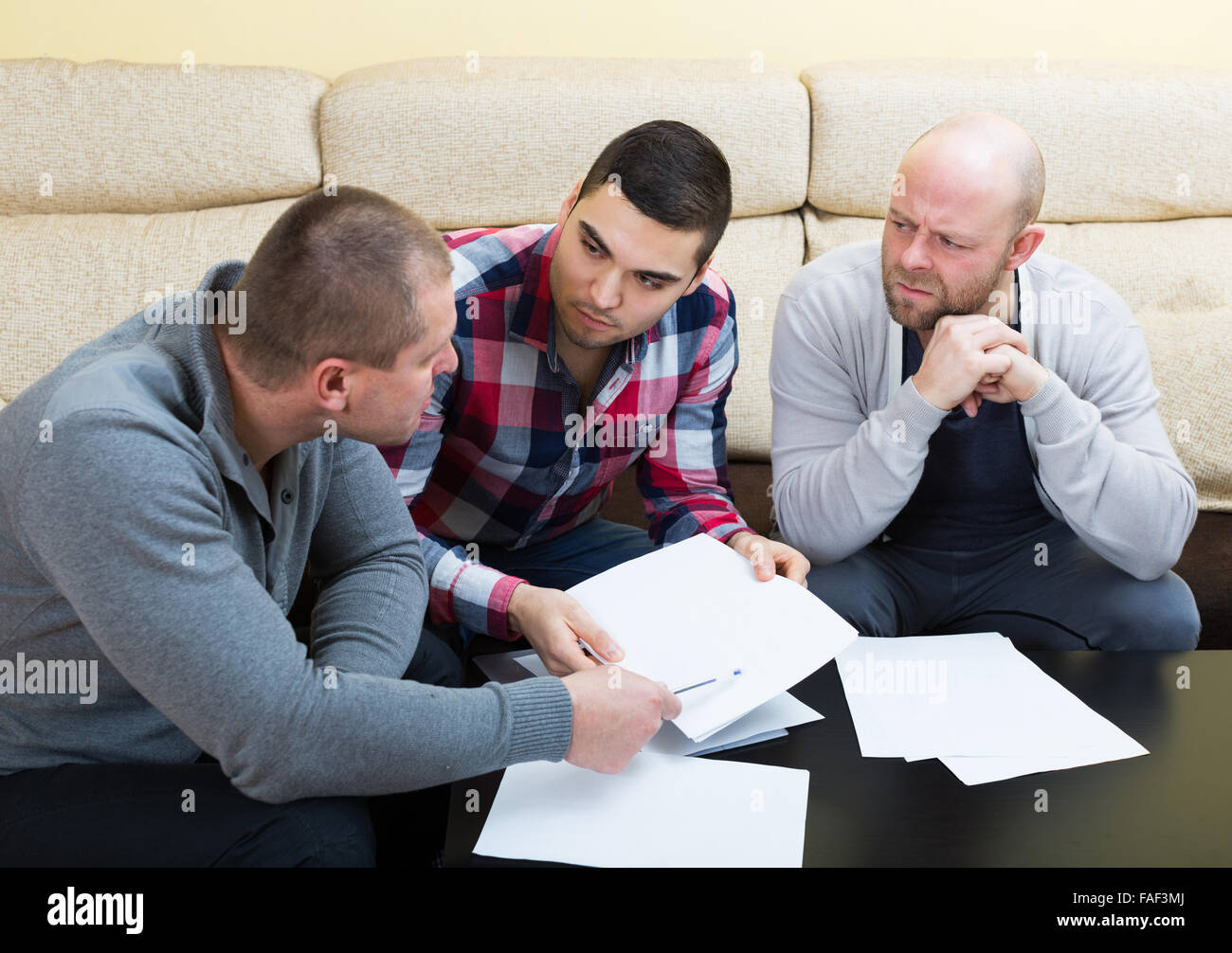 Three men with documents discussing financial issues Stock Photo - Alamy