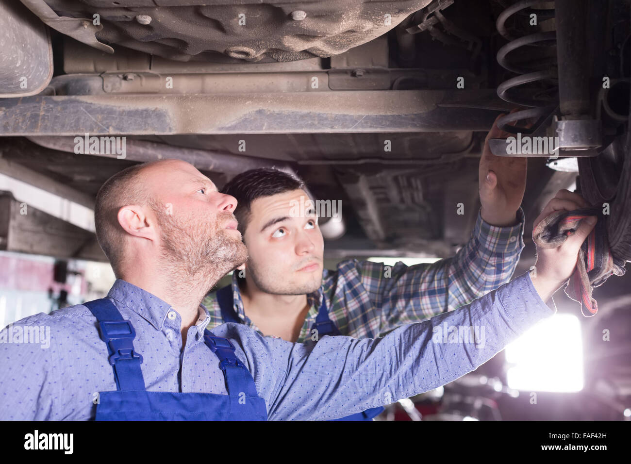 Two adult american man fixing car tire leak Stock Photo - Alamy